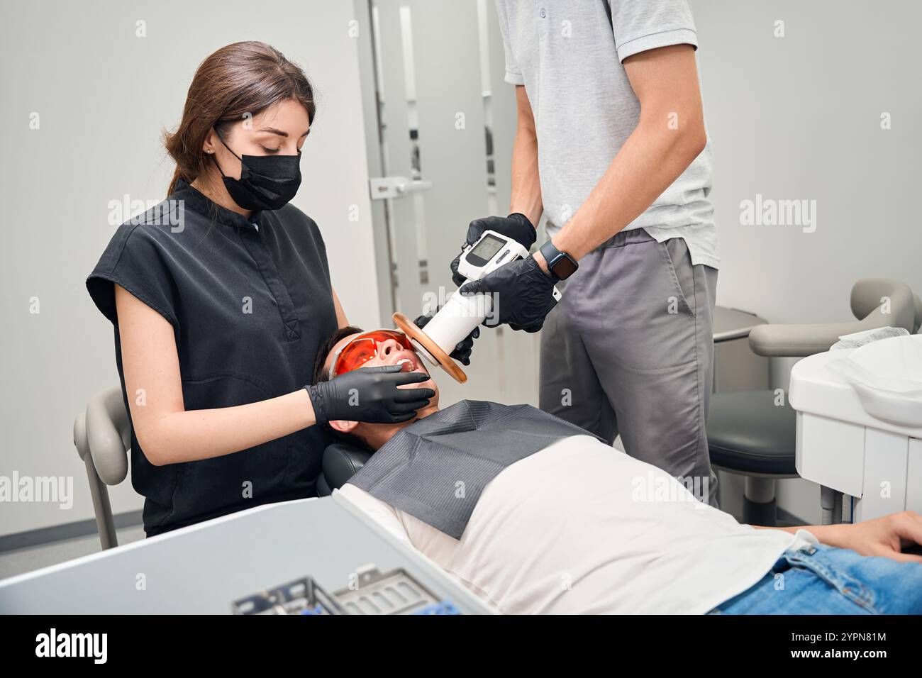 Qualified dentist team using portable x-ray device to check teeth roots ...