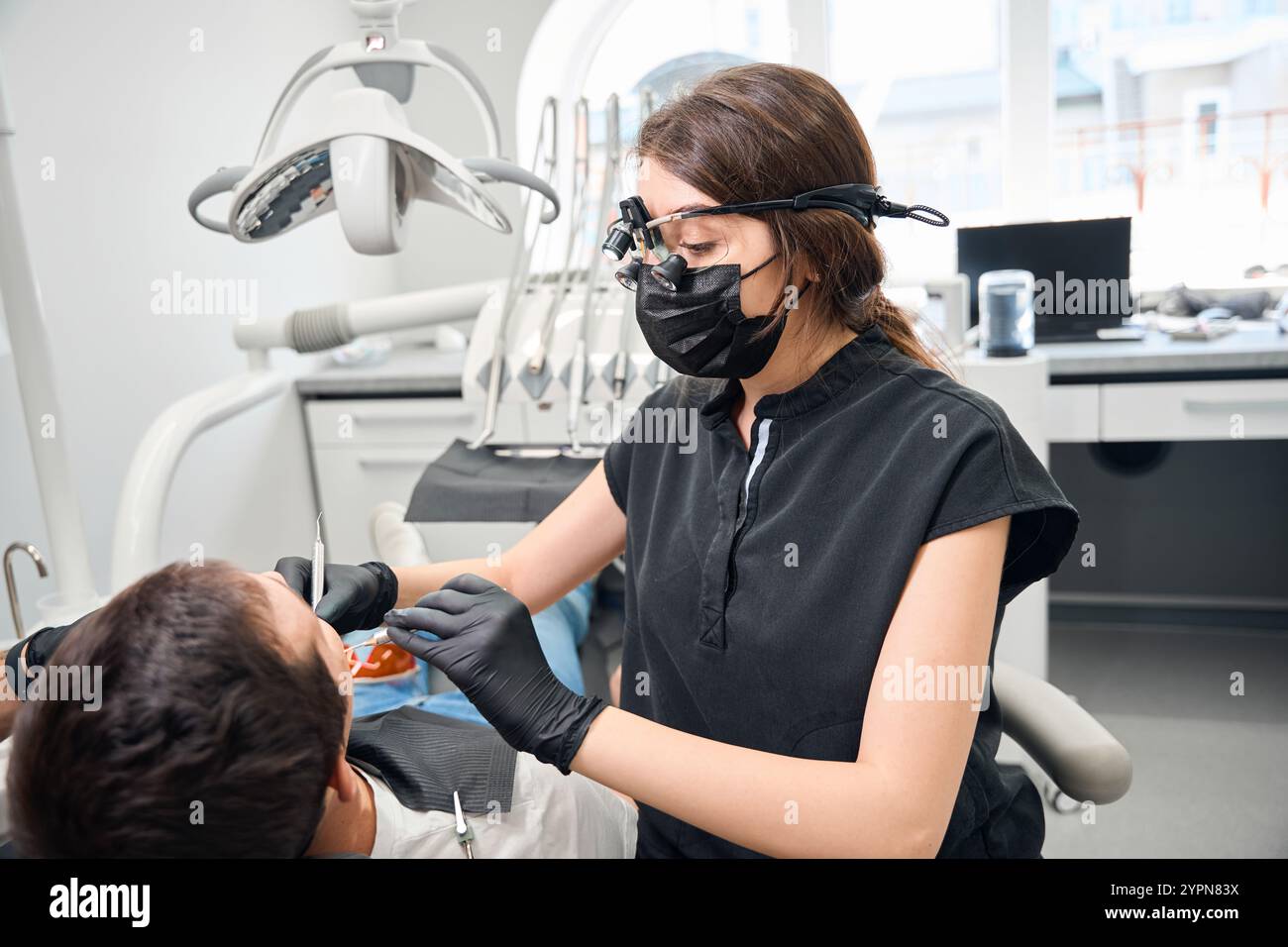 Serious woman dentist cleaning root canals using special dental tools ...
