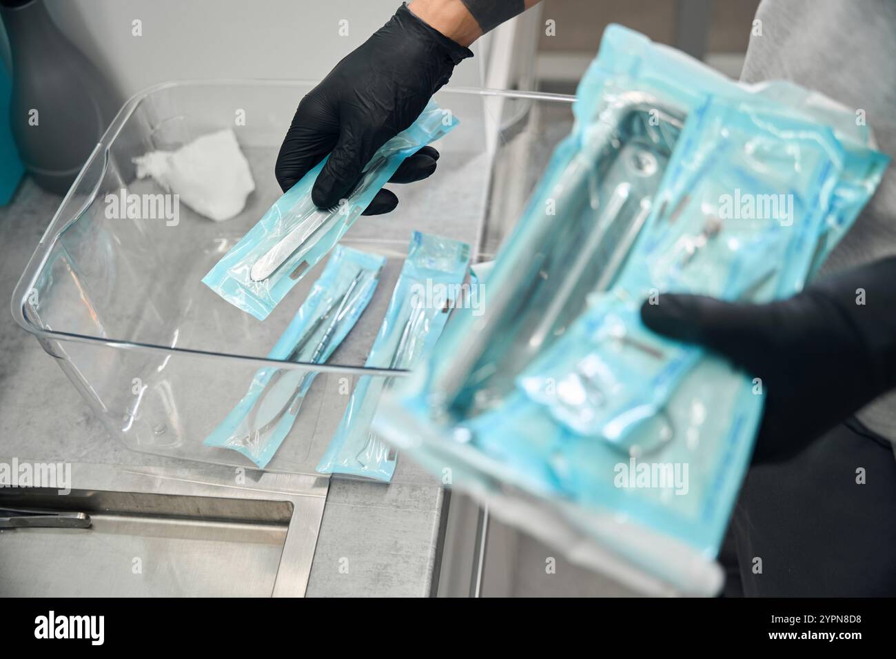 Dental technician in rubber gloves taking packages with sterile tools ...