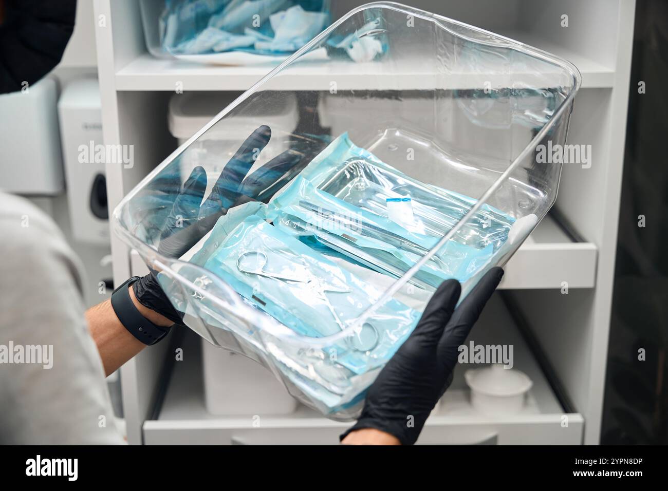 Man dentist holding plastic container with closed packages with sterile ...