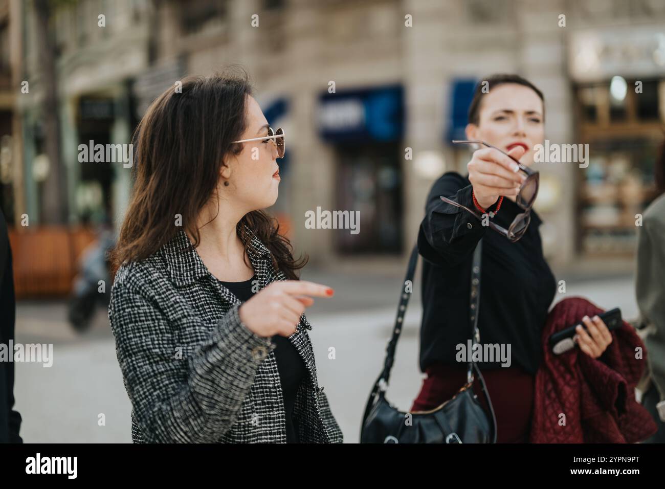 Two women discussing directions on a city street in daylight Stock ...