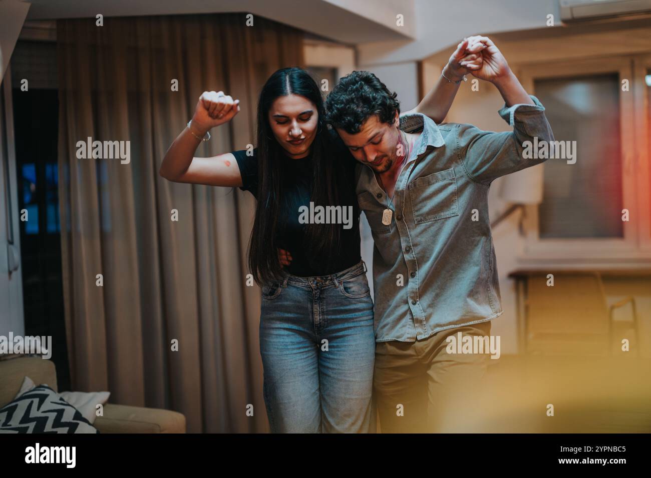 Young couple dancing joyfully inside their cozy living room Stock Photo ...