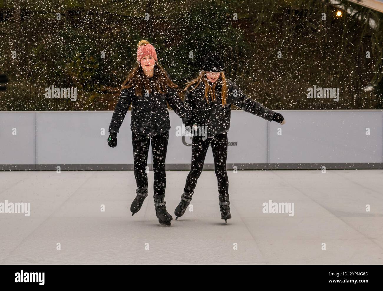 Two girls skating on a sustainable eco-friendly ice skating rink with ...