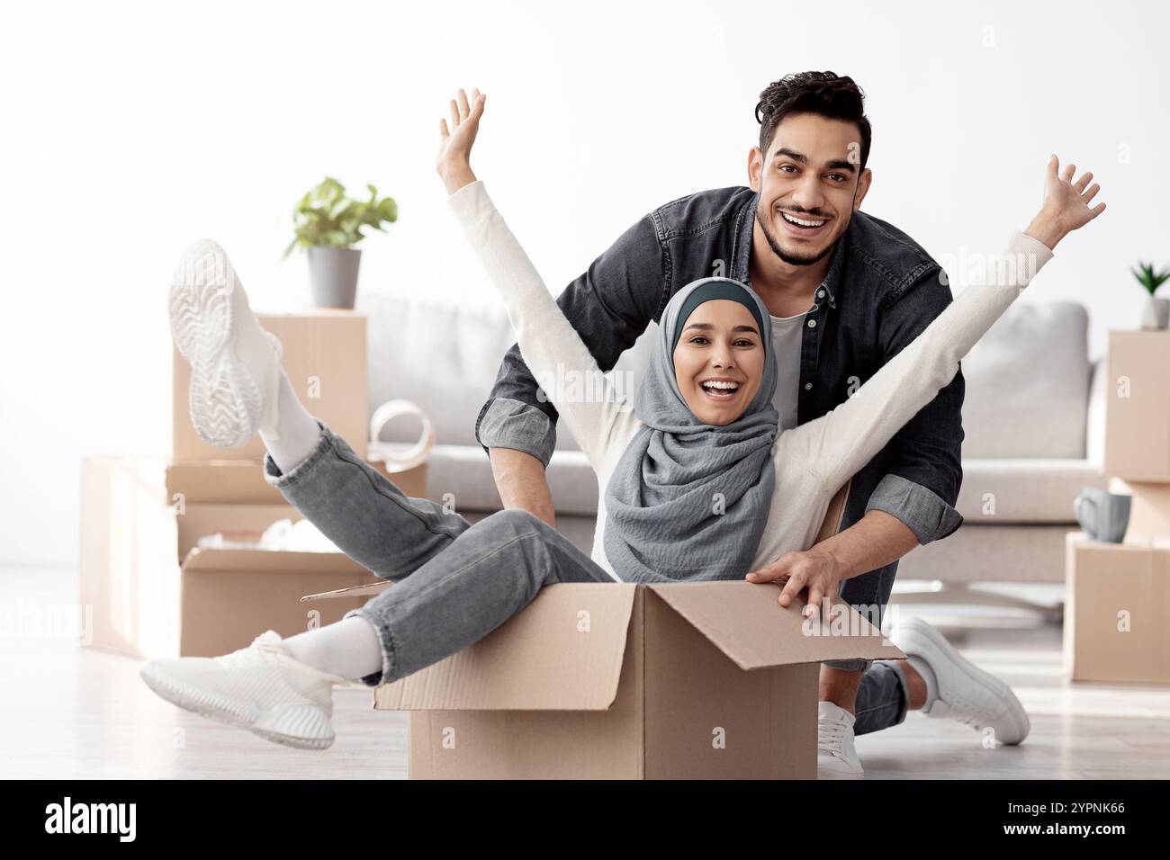 Positive muslim family playing with packing supplies while moving Stock ...