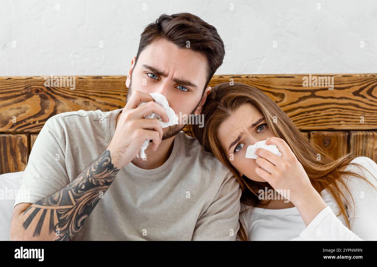 Self-isolation together. Young man and woman in bed wipes nose with napkins Stock Photo - Alamy