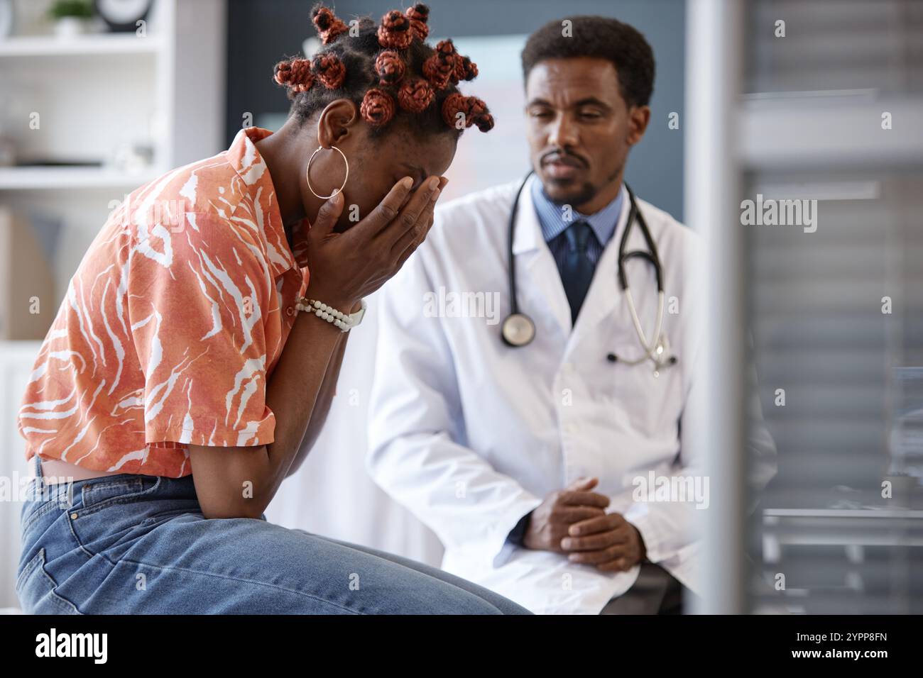 Side view of African American woman crying in doctors office and ...