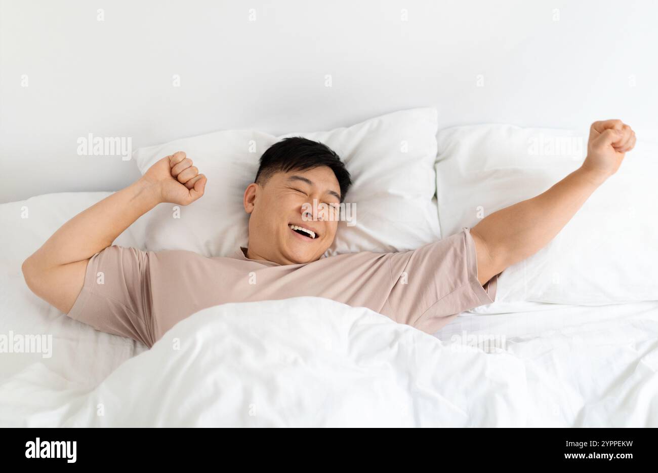 Top view of smiling asian man stretching in bed Stock Photo - Alamy