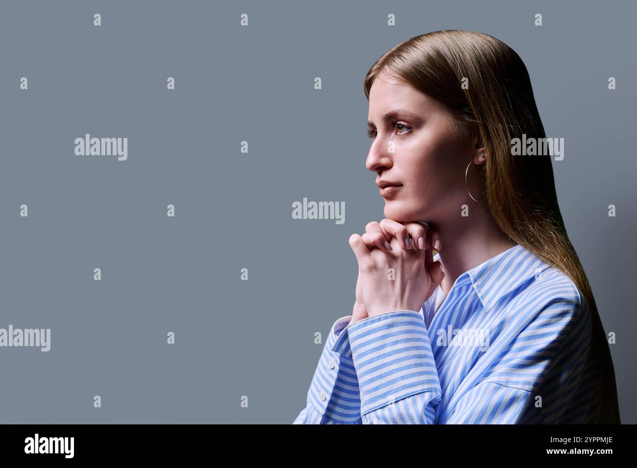 Profile view, young serious female looking forward on gray studio ...
