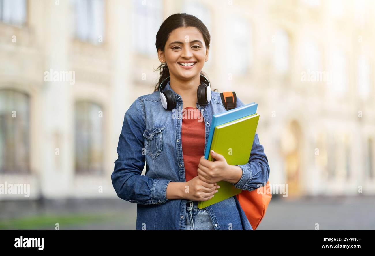 Happy pretty young indian lady student posing at university campus ...