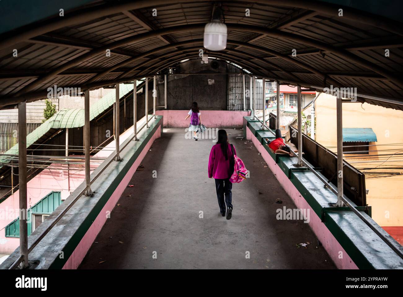 Pedestrians make their way along a footbridge over a busy road in ...