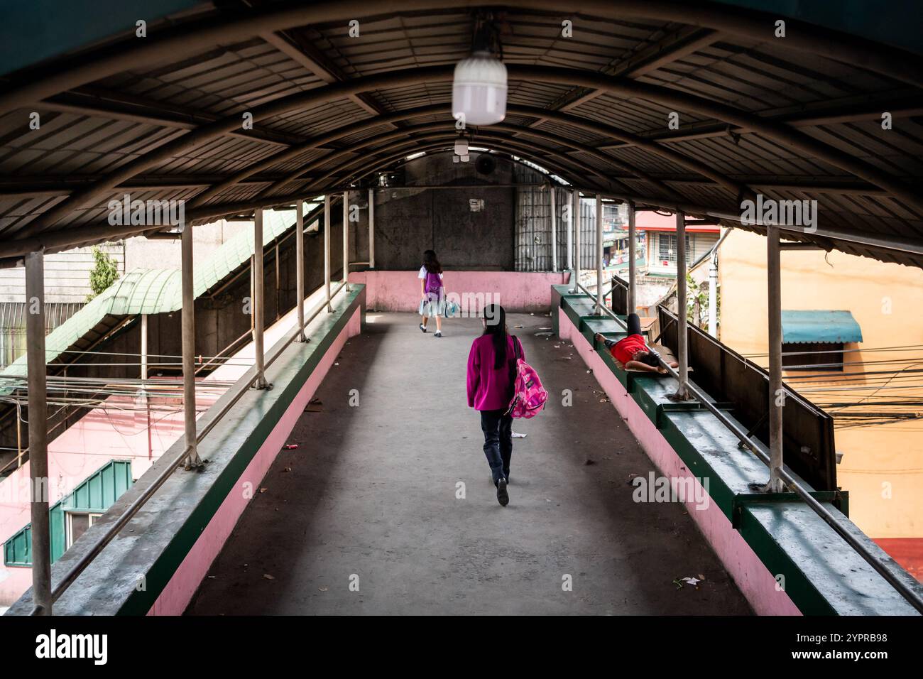 Pedestrians make their way along a footbridge over a busy road in ...