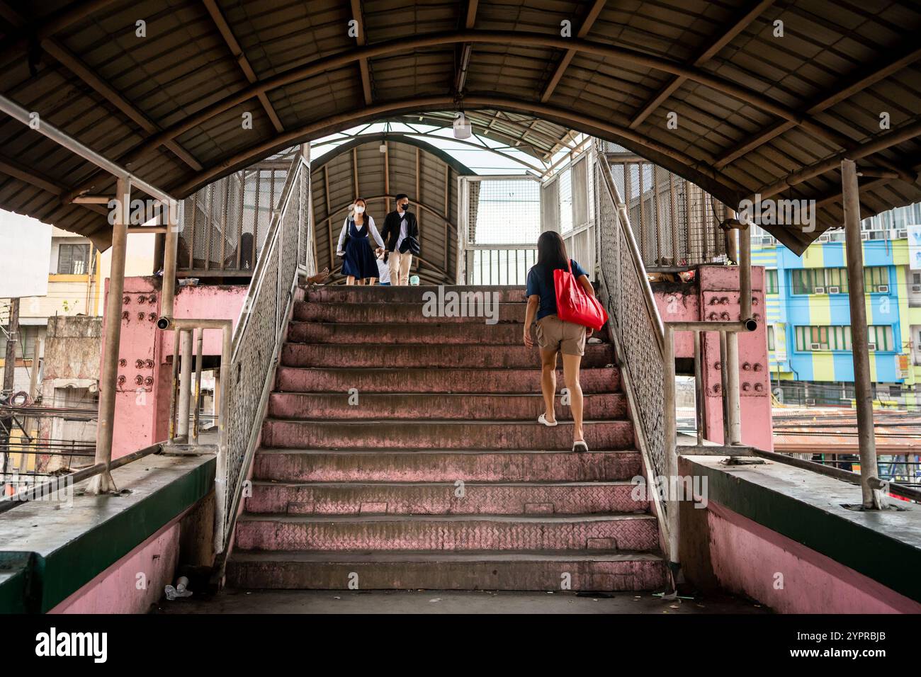Pedestrians make their way along a footbridge over a busy road in ...