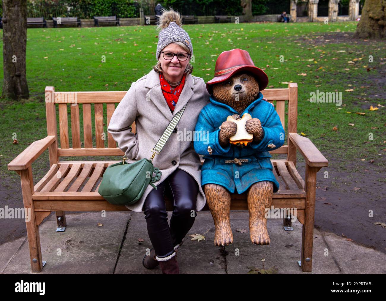Woman sitting on a bench next to a life-sized Paddington Bear statue in ...