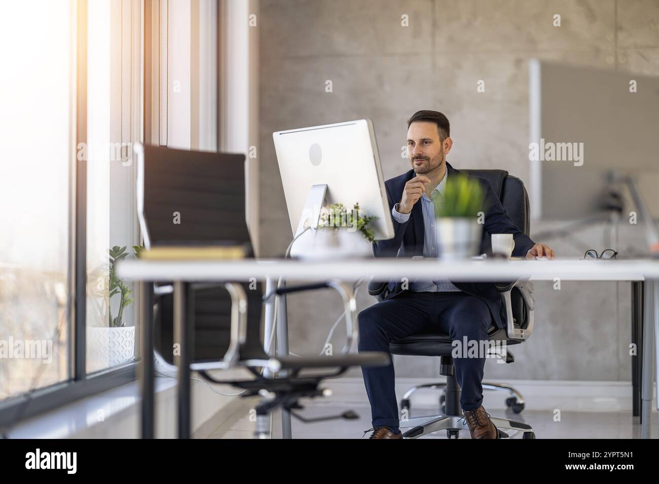 A professional businessman in a modern office setting, working at his ...