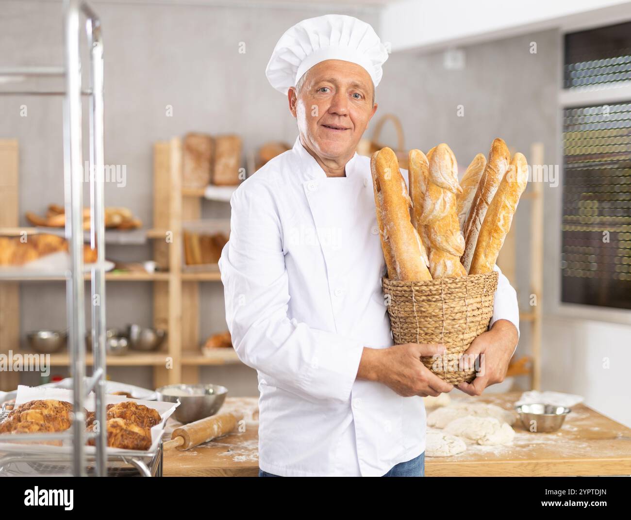Bakery mature man employee holds basket of ready-made baguettes Stock ...
