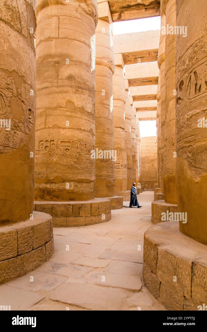 An Egyptian man walks through the huge columns of the Great Hypostyle ...