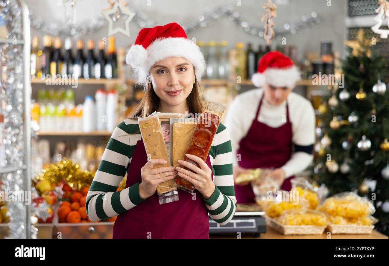 Young woman seller offering nougat in grocery store Stock Photo - Alamy