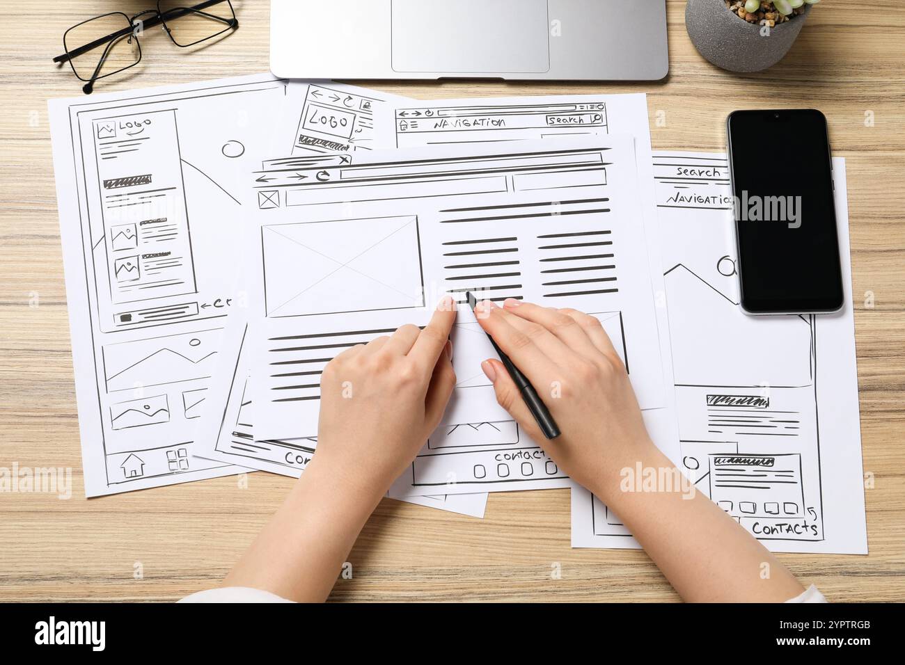 Website designer creating wireframe on paper with pen at wooden table ...