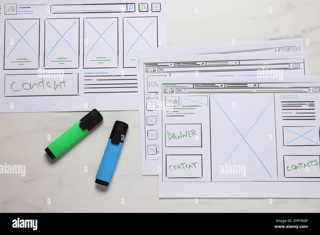 Developing UI design. Sketches of website wireframes and felt pens on white marble table, top ...