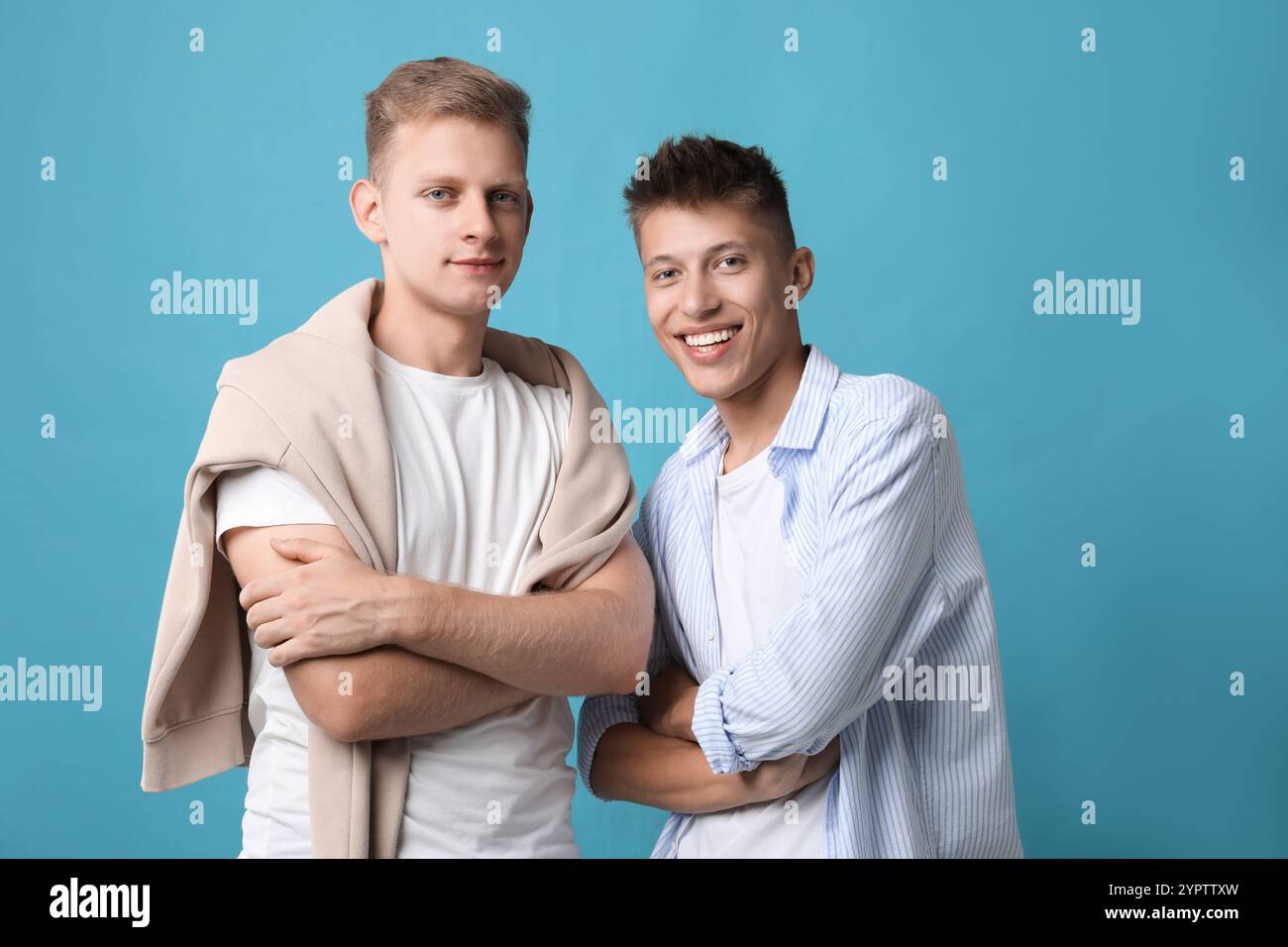 Happy brothers posing with crossed arms on light blue background Stock ...