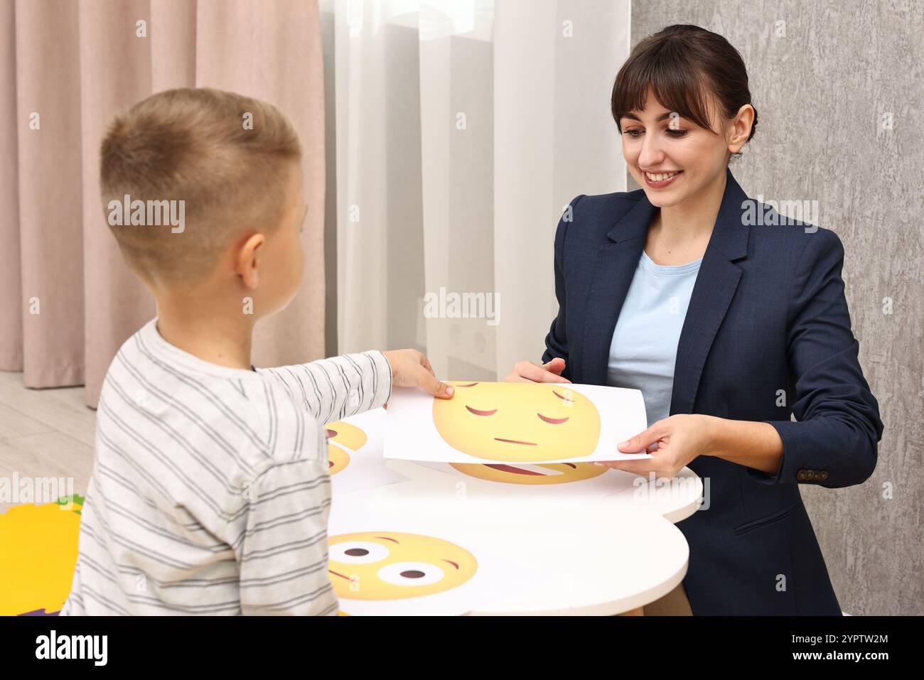 Autism therapy. Little boy choosing emoticon at table with smiling ...