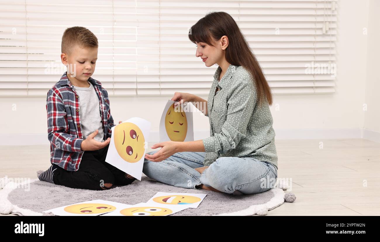 Autism therapy. Little boy choosing emoticon with psychologist in ...