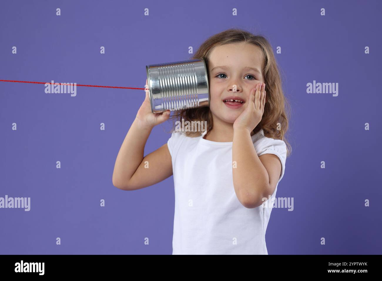 Excited girl using tin can telephone on violet background Stock Photo ...