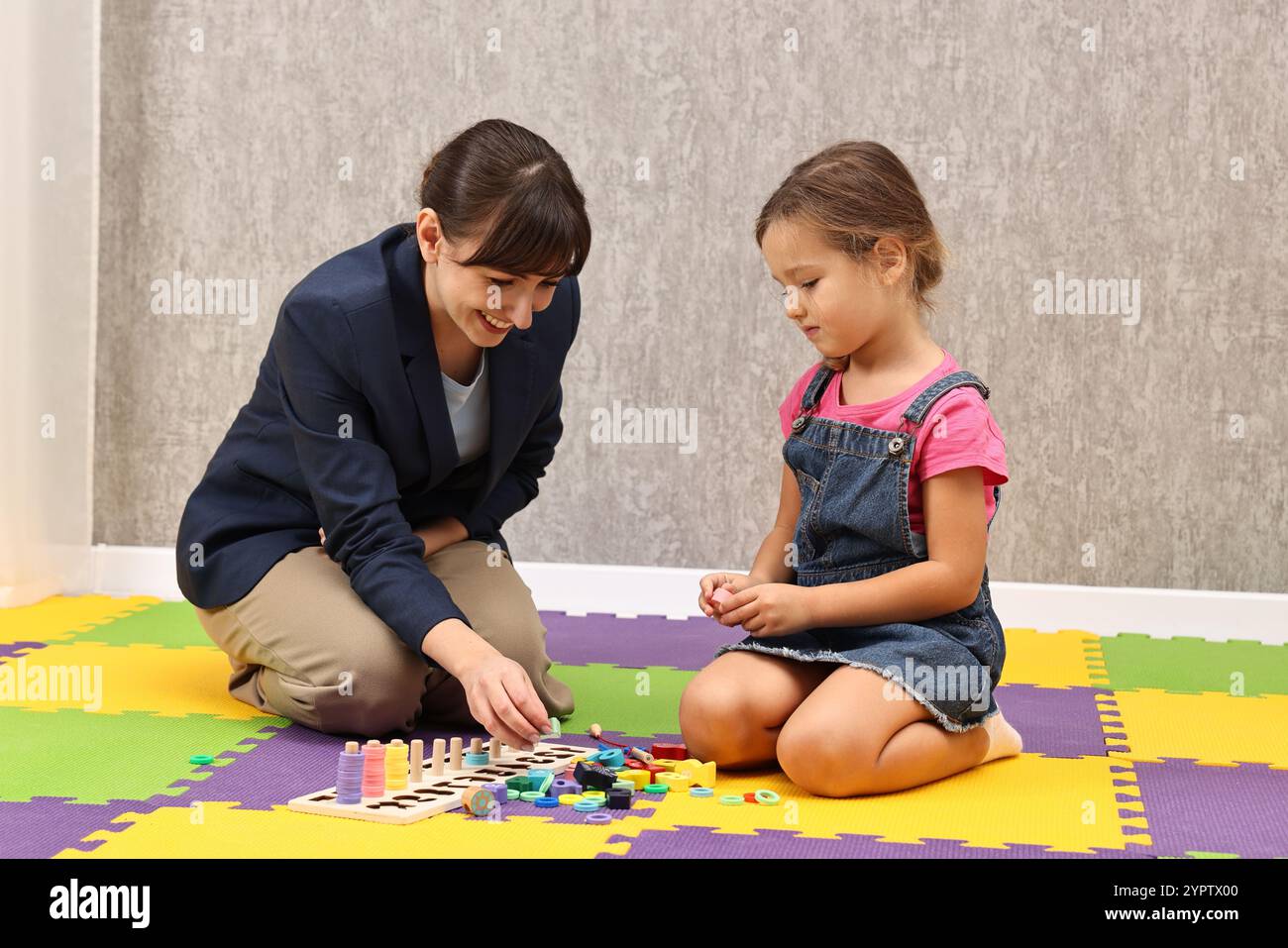 Autism therapy. Smiling psychologist and little girl playing with ...