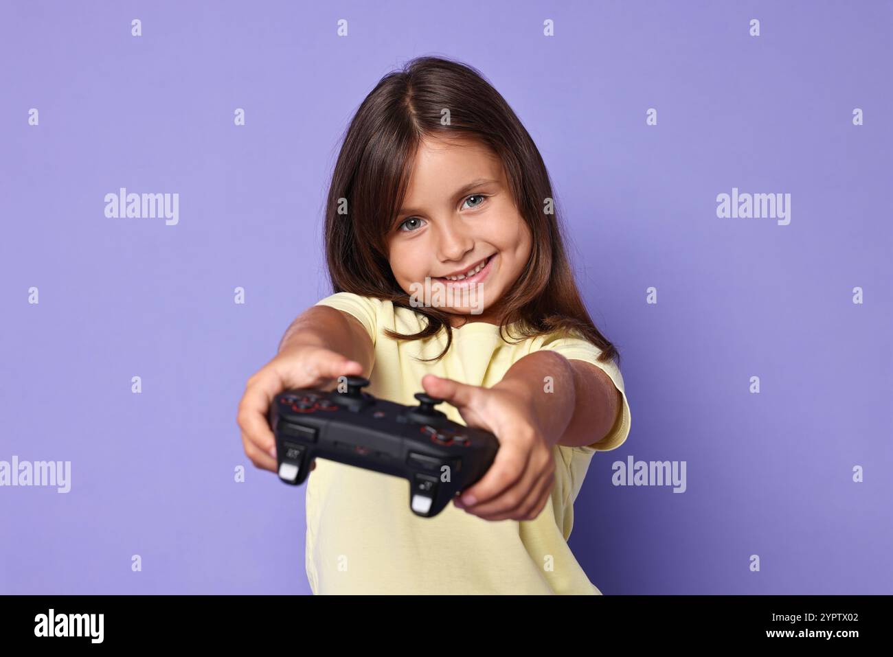 Happy little girl playing video game with controller on violet ...