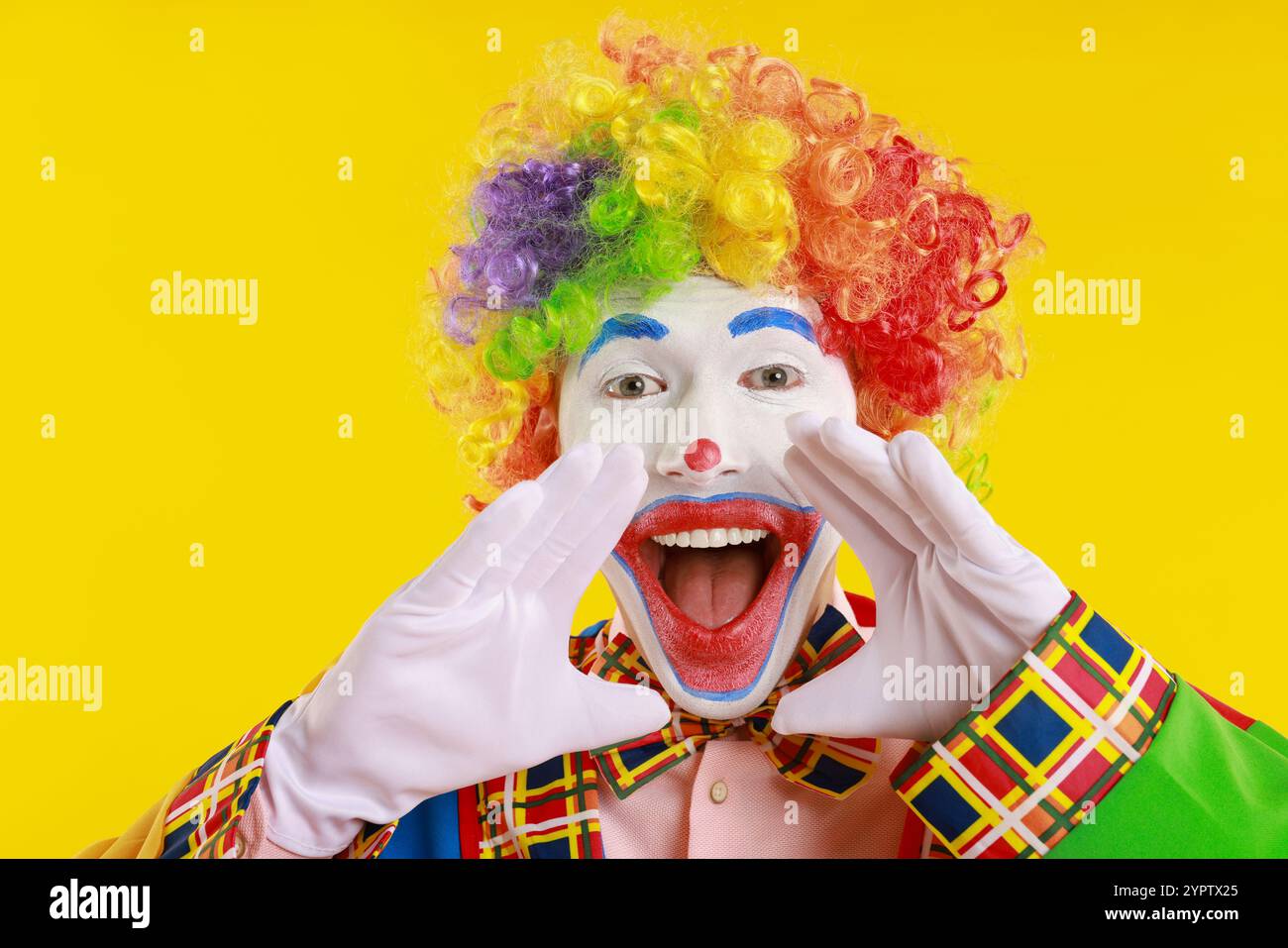 Portrait of clown screaming on yellow background Stock Photo - Alamy