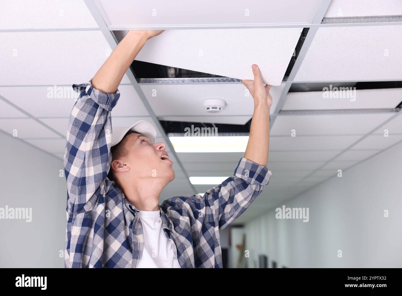 Suspended ceiling installation. Builder working with PVC tile indoors ...