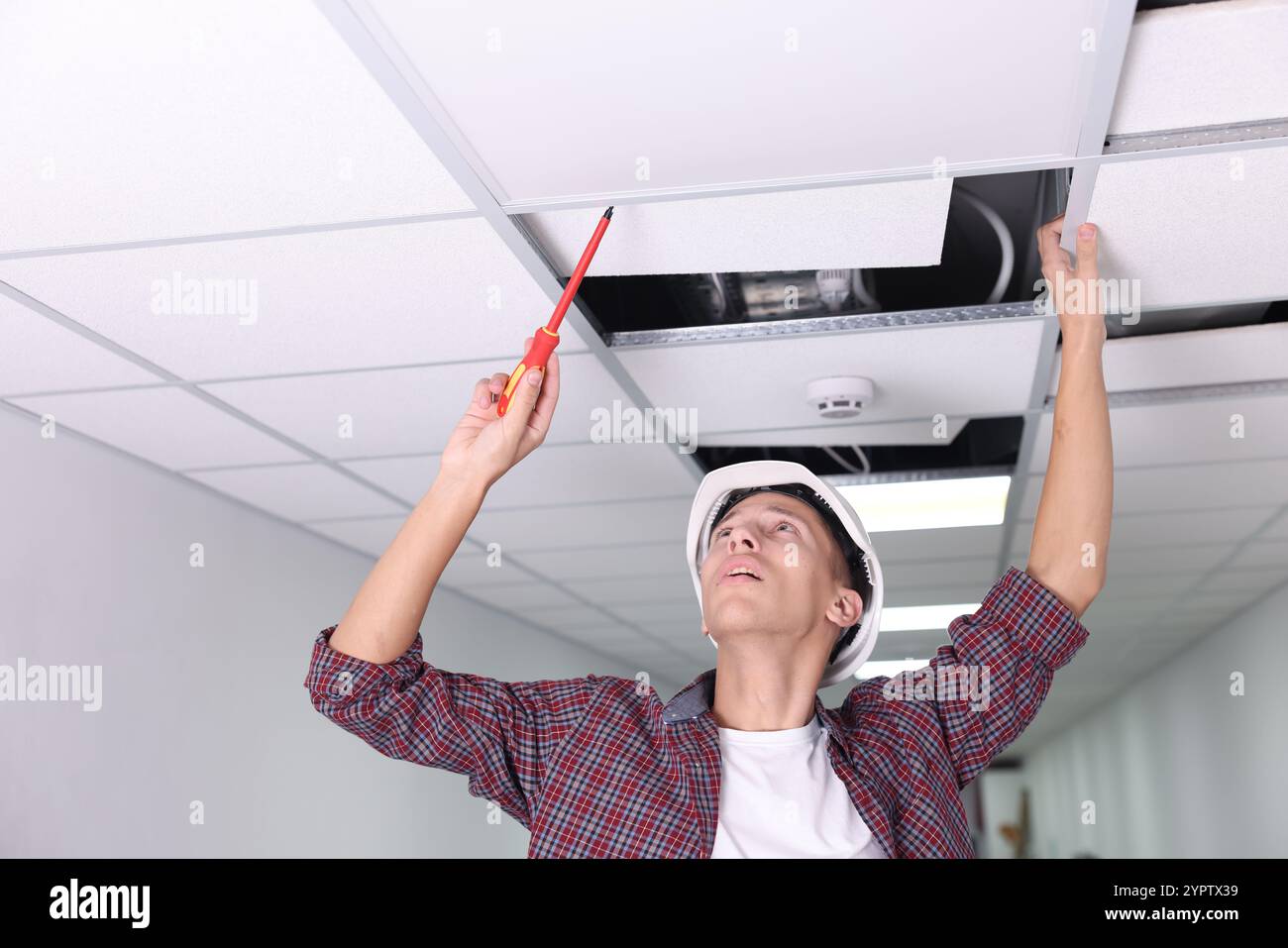 Suspended ceiling installation. Builder working with PVC tile indoors ...