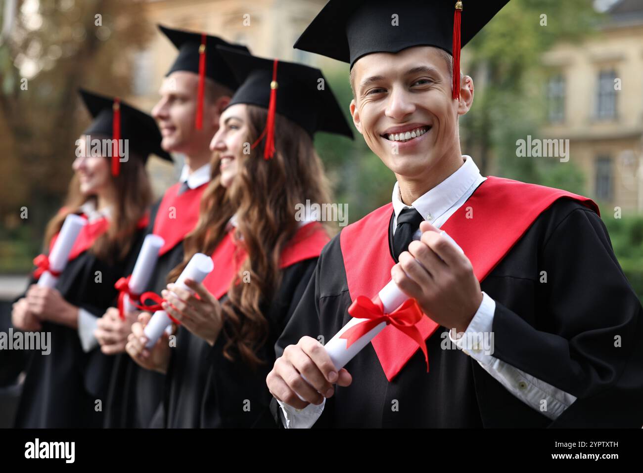 Happy students with diplomas after graduation ceremony outdoors ...