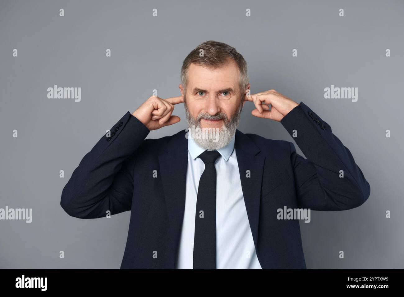 Senior man covering his ears with fingers on grey background Stock ...