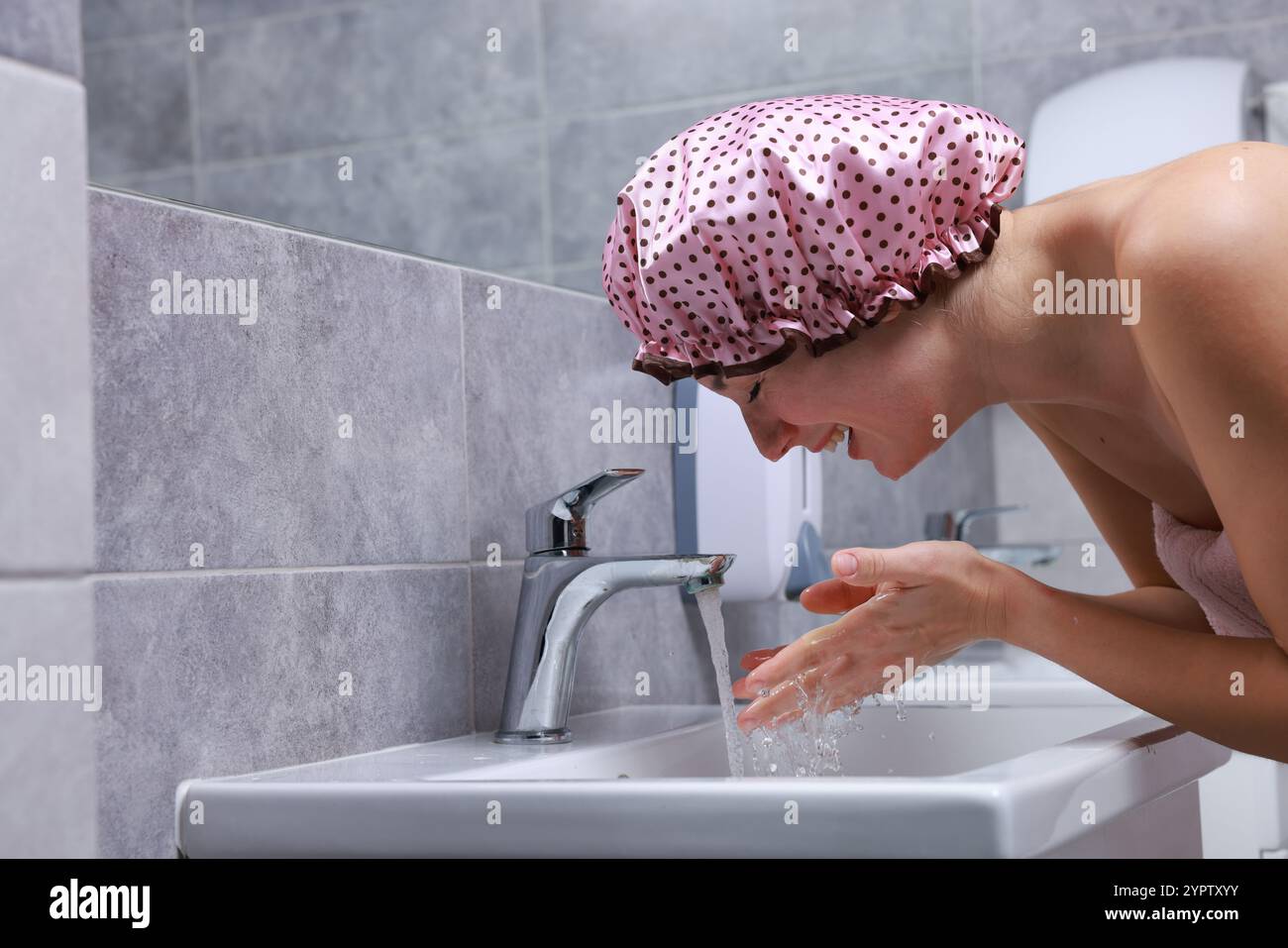 Woman with shower cap washing her face in bathroom Stock Photo - Alamy