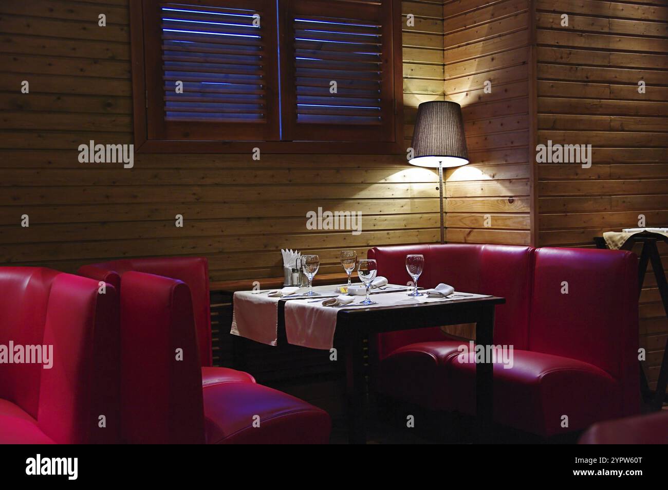 A cozy corner in a cafe, a table with a floor lamp in the twilight ...