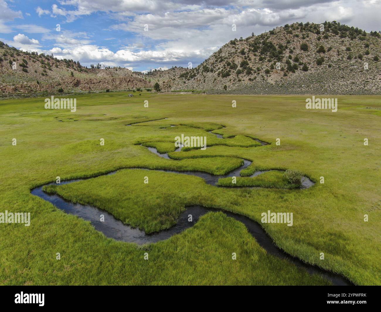 Aerial view of green land and small curve river with mountain in the ...