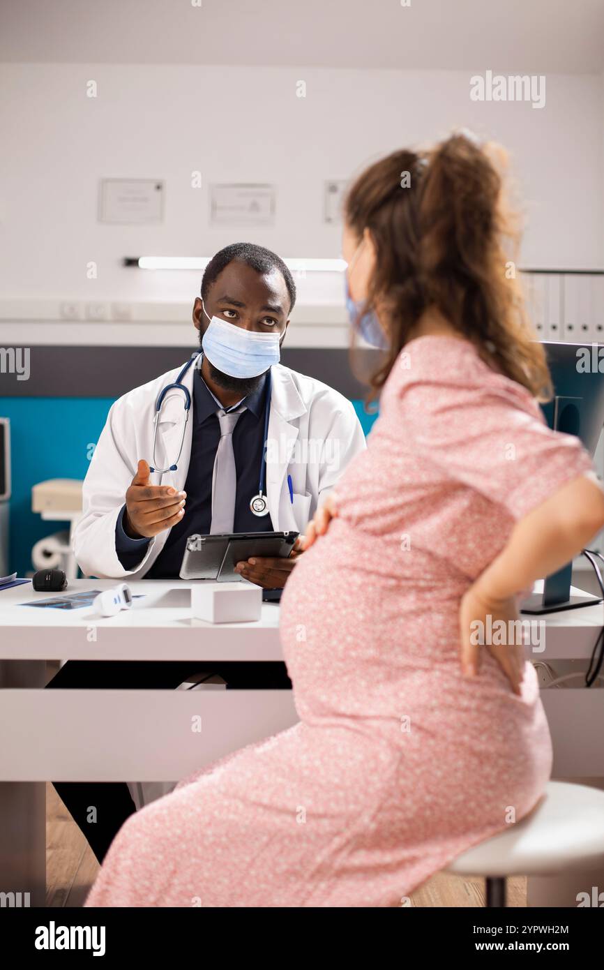 Male obstetrician discusses pregnancy care with white woman during ...