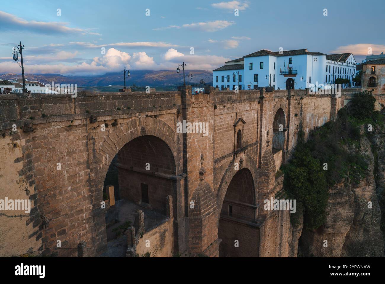 The iconic Puente Nuevo bridge in Ronda, Spain, features massive stone arches. A white building ...
