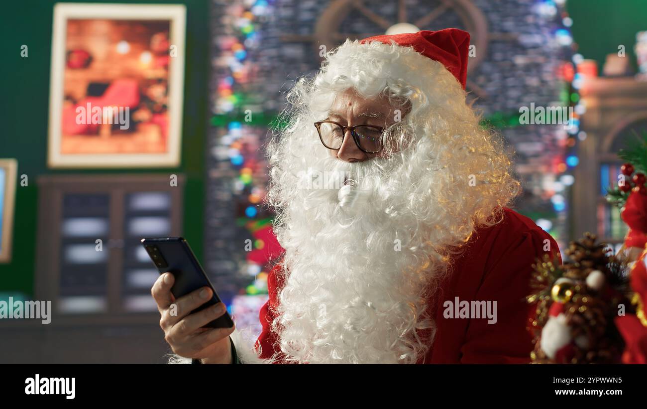 Santa Claus navigates web on his smartphone and checking gift lists and ...