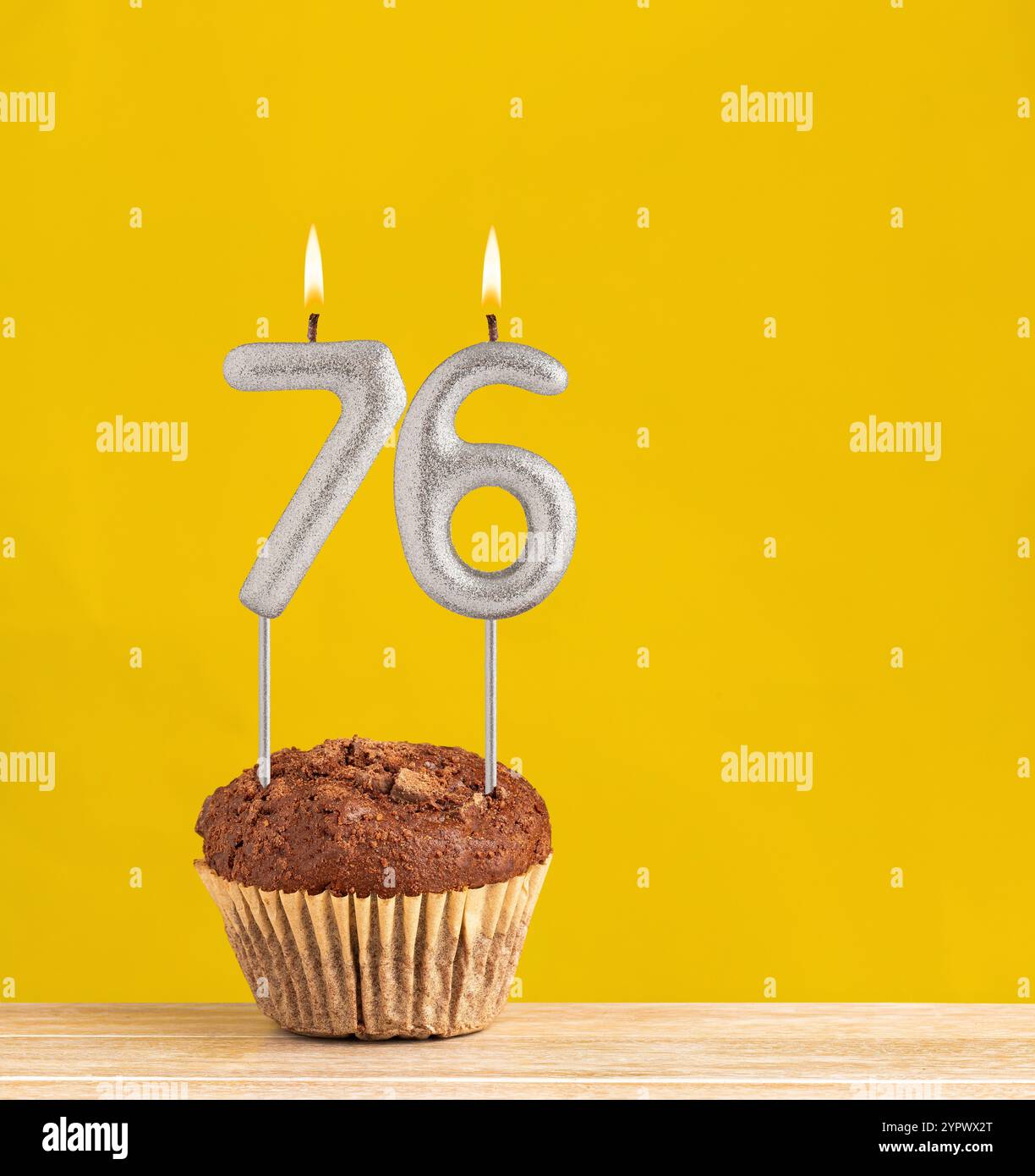Chocolate cupcake with number 76 candle - Birthday on a yellow ...