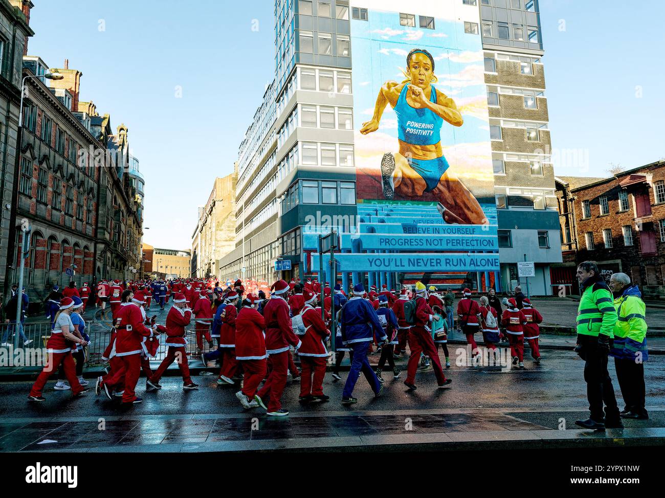 Participants run past mural during the Liverpool Santa Dash 2024 ...