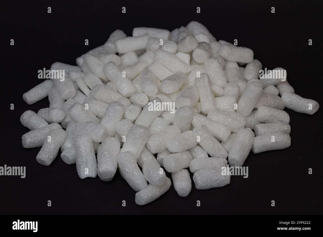 Pile of white polystyrene foam packaging peanuts on a black background ...