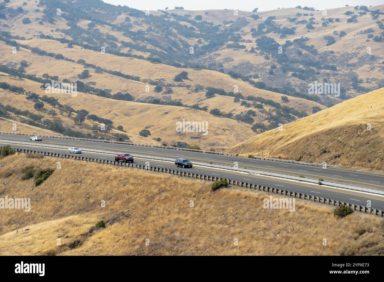 Freeway road with cars crossing the the San Luis Reservoir valleys during dry and hot season ...