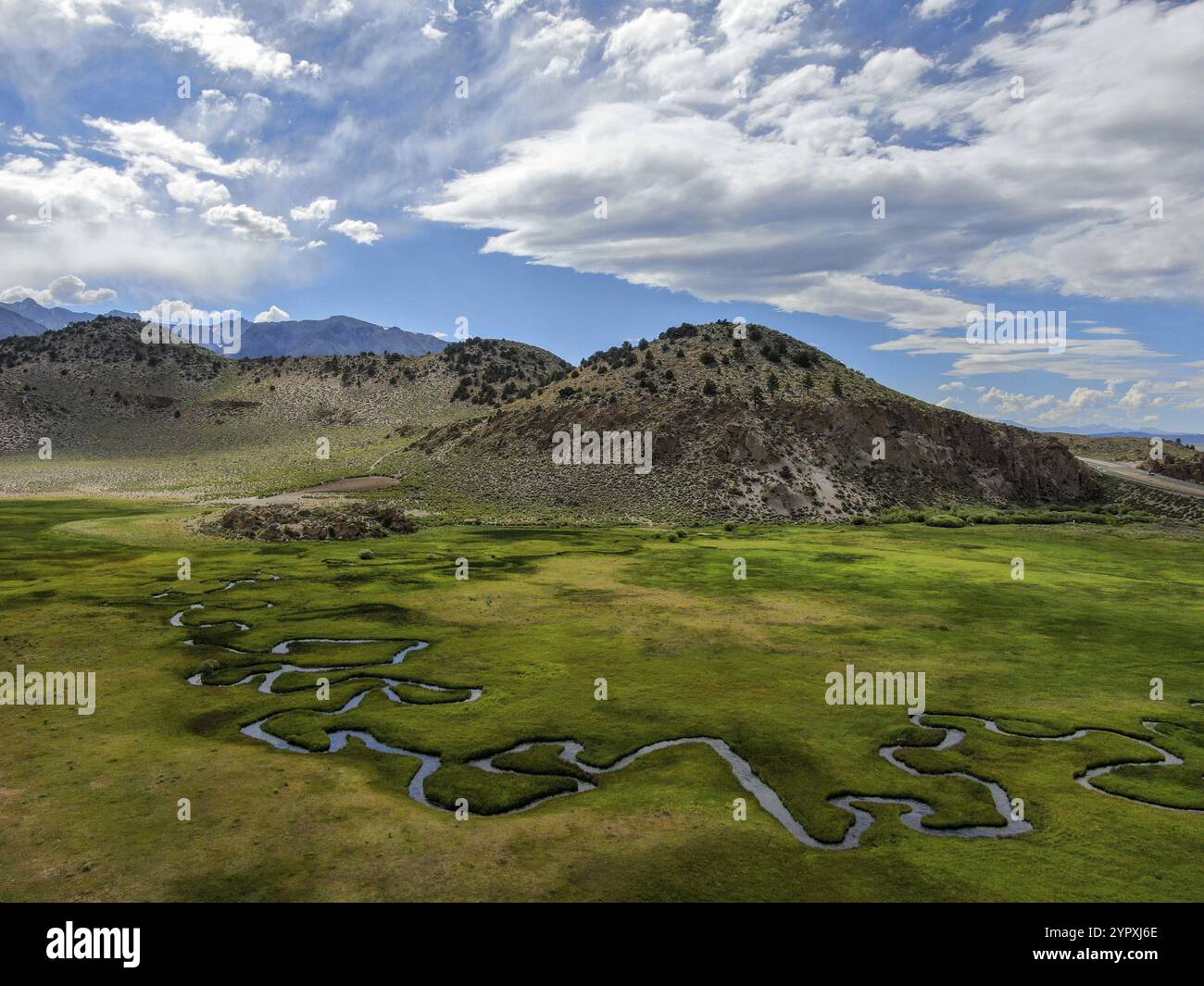 Aerial view of green land and small curve river with mountain in the ...