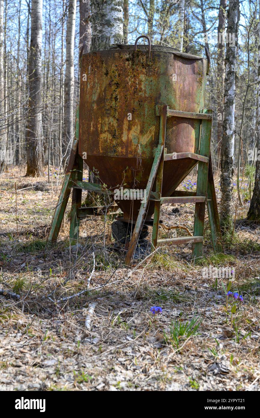 A large metal old rusty abandoned cylinder with a funnel in the spring ...