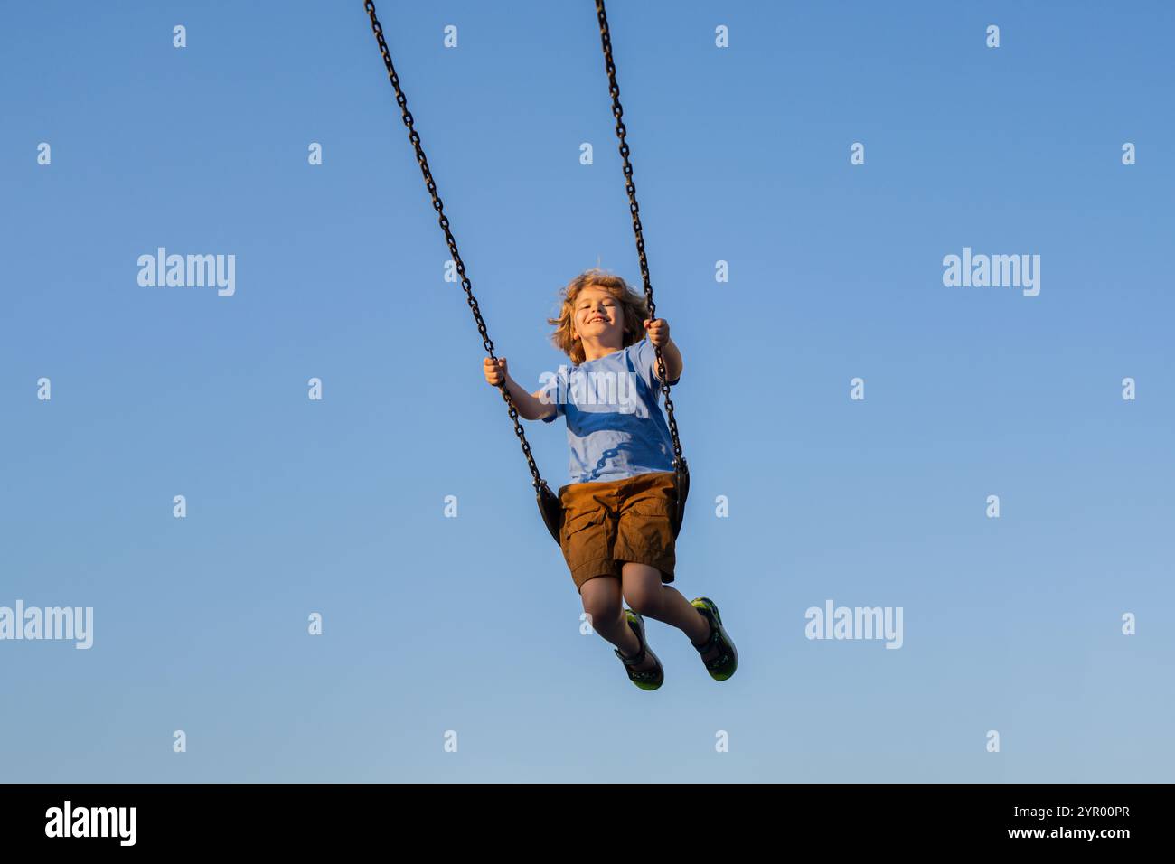 Joyful kid swinging on a swing. Happiness children. Child having fun on ...