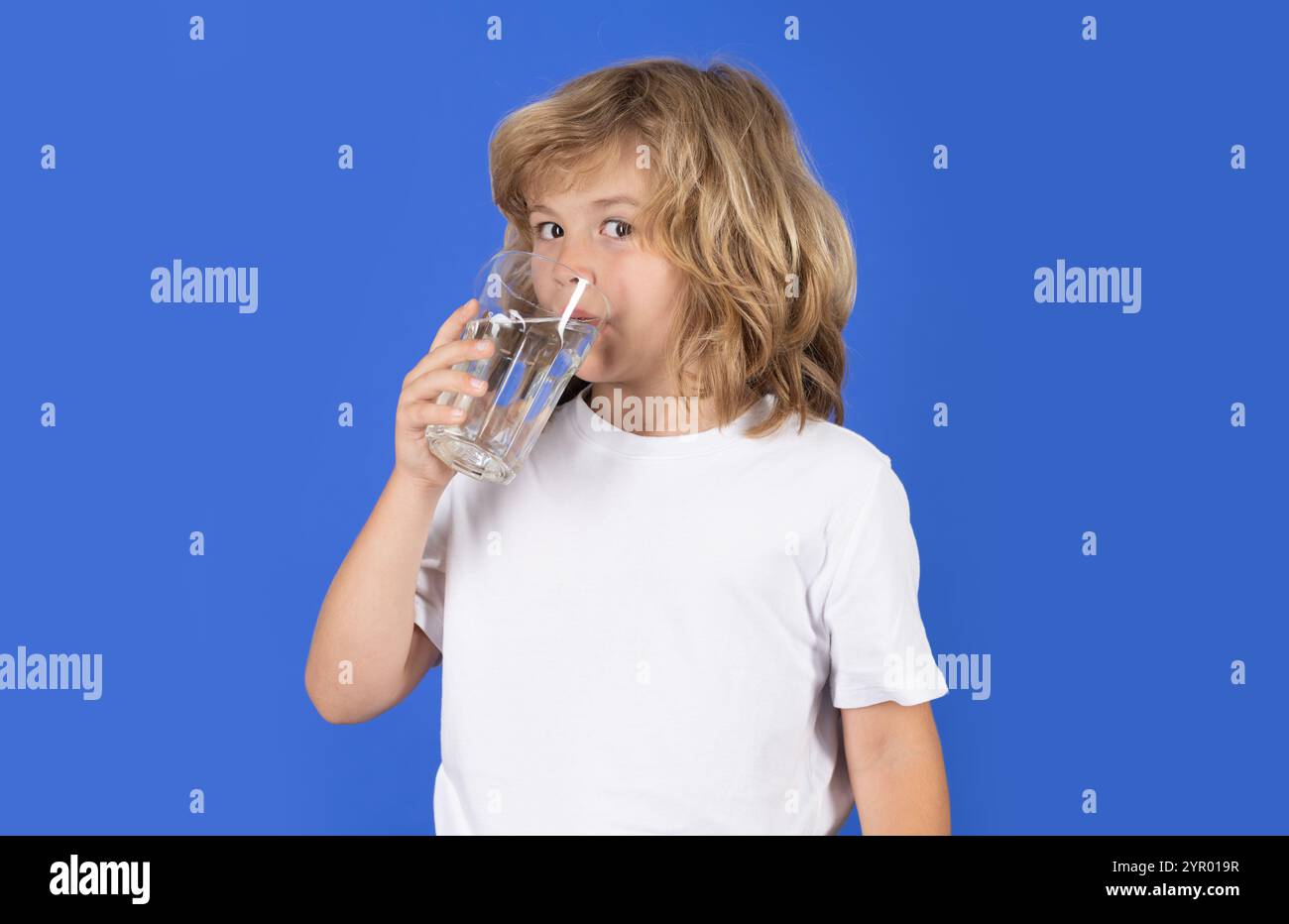 Kid drinking a fresh glass of water, isolated on studio background ...
