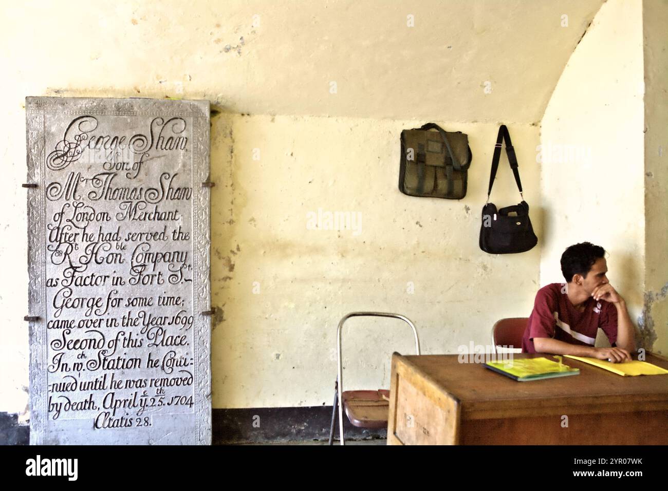 A man sitting behind a desk that is used as a ticket counter for ...