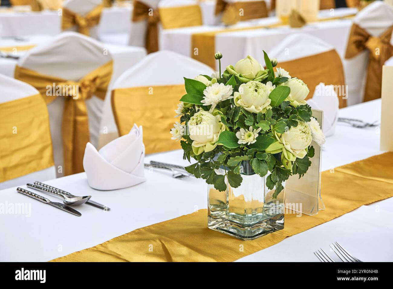 Elegant wedding reception table with floral centerpiece and gold decorations in a banquet hall ...